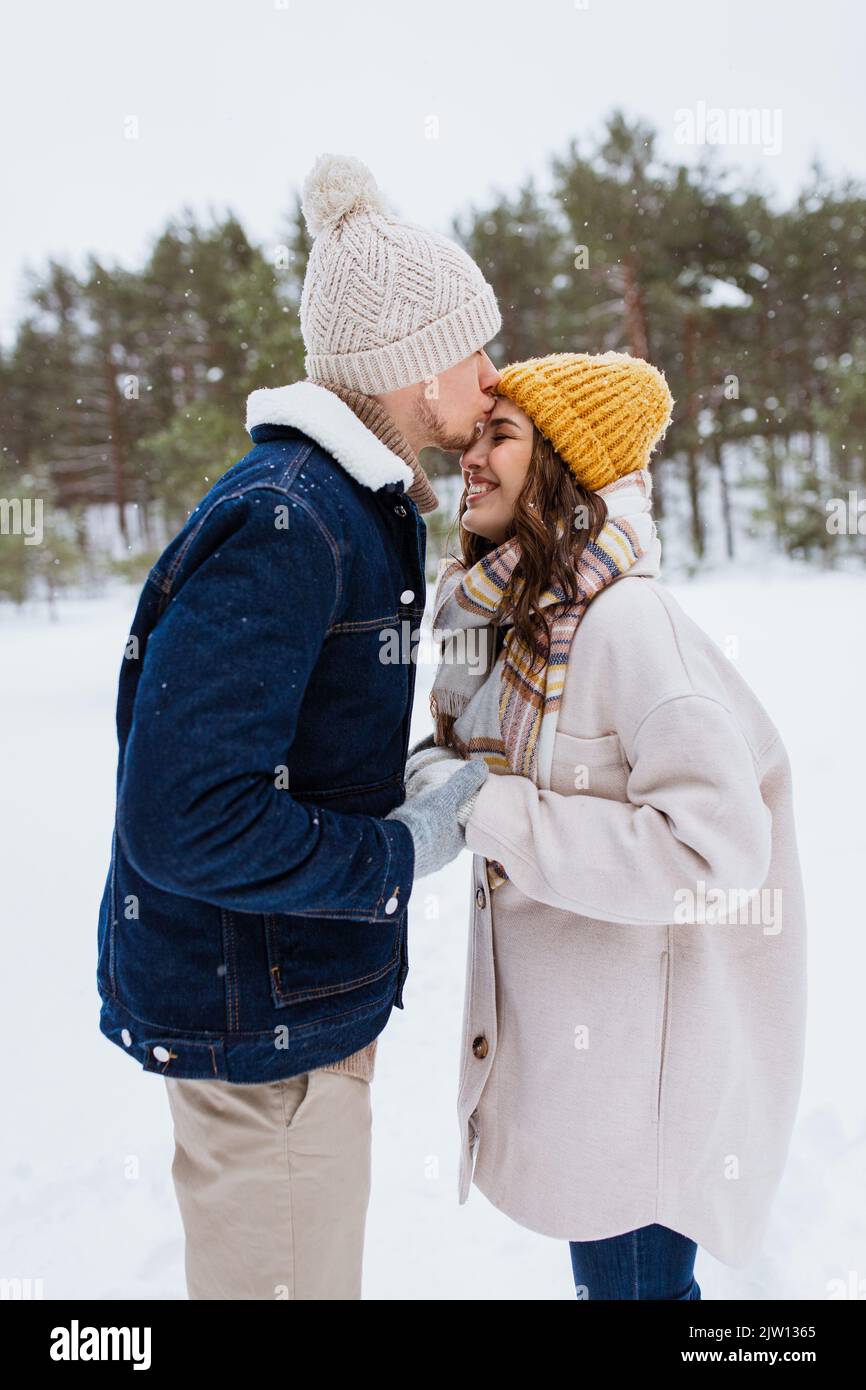 happy man kissing woman to forehead in winter Stock Photo - Alamy