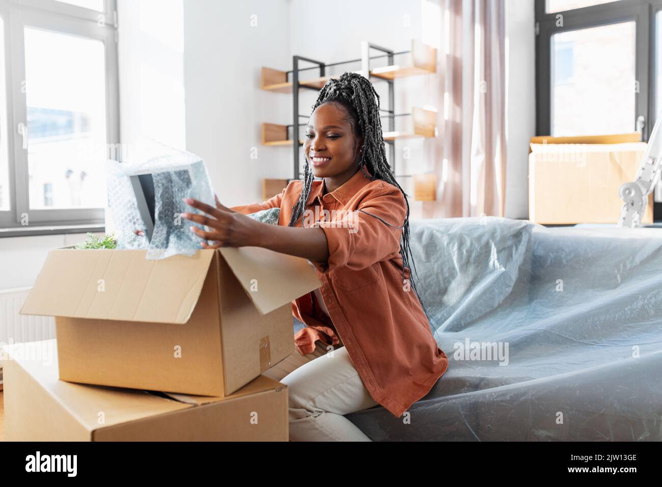 happy woman packing boxes and moving to new home Stock Photo - Alamy