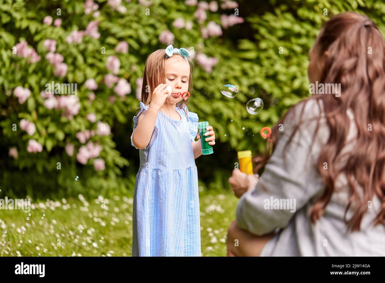 mother with daughter blowing soap bubbles at park Stock Photo - Alamy