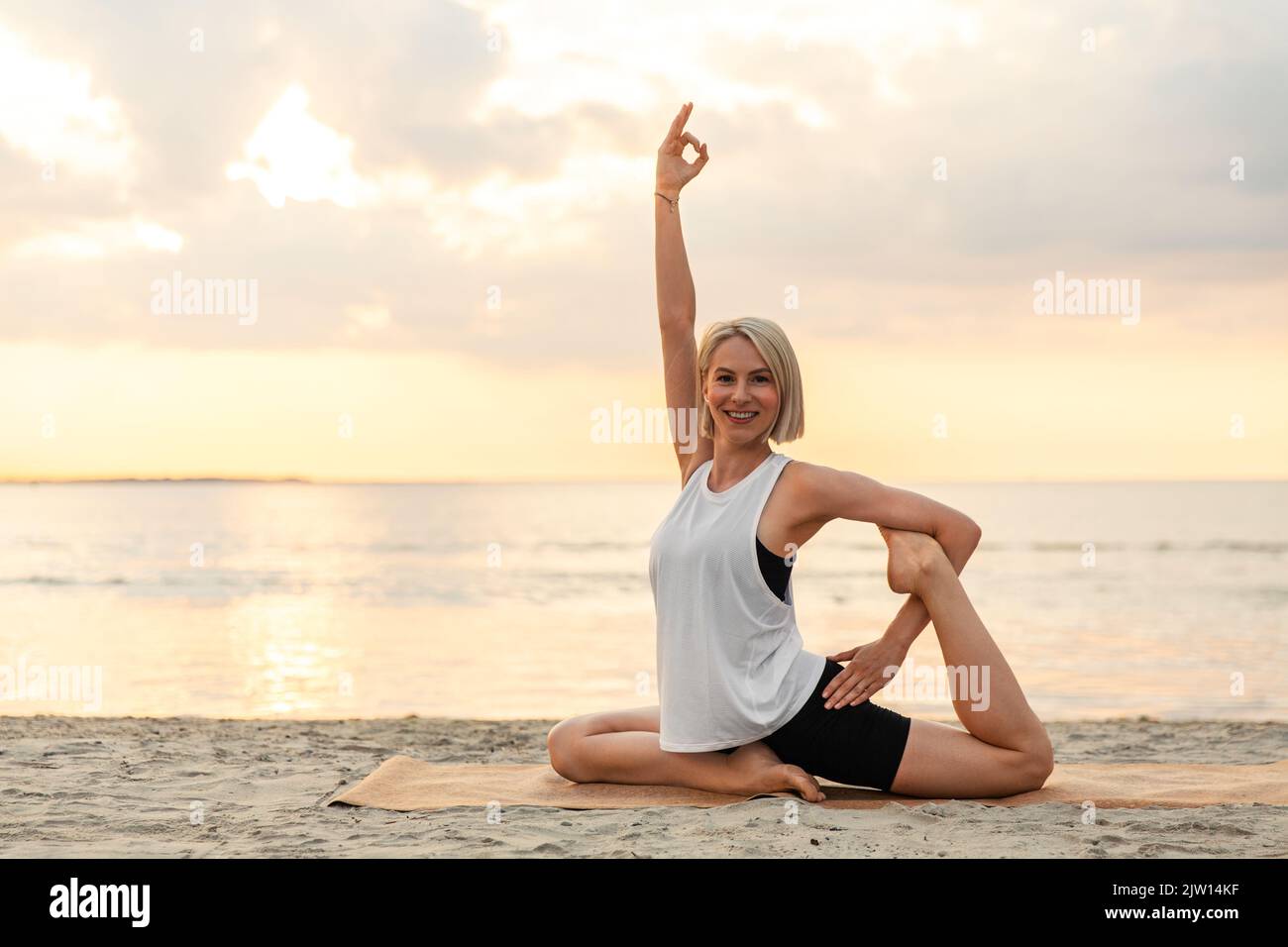 woman doing yoga mermaid pose on beach Stock Photo - Alamy