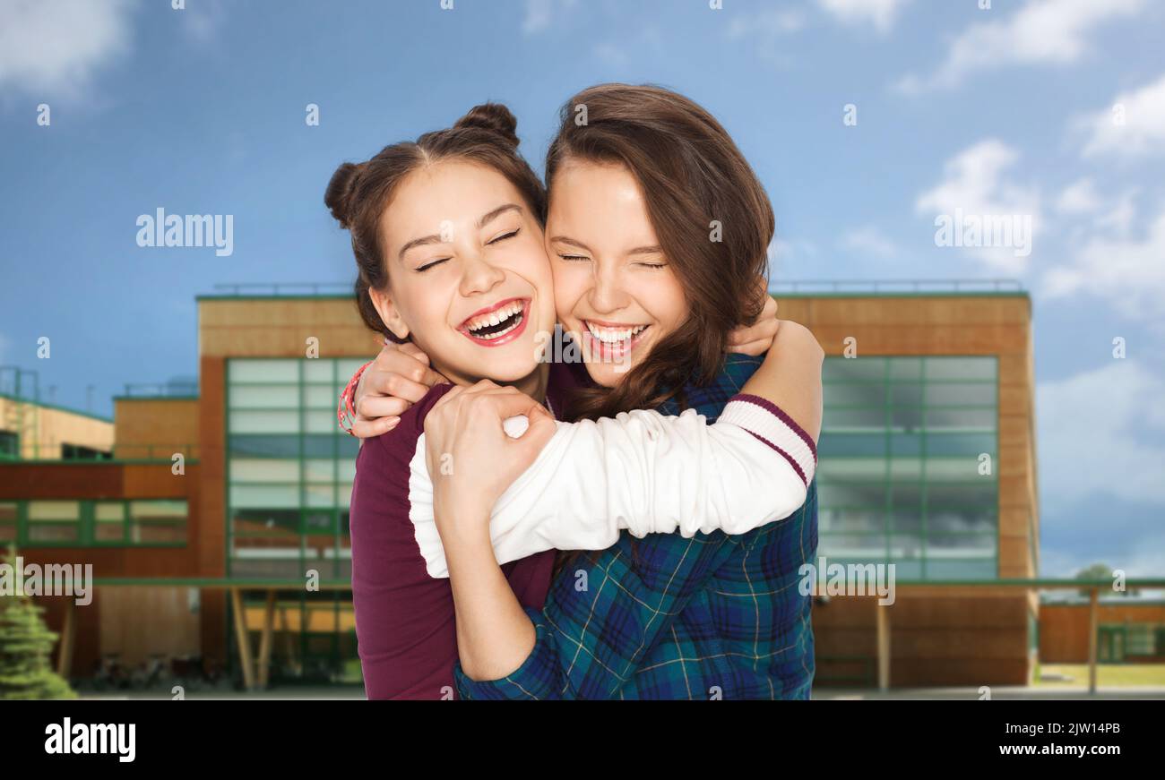 happy teenage girls hugging on school background Stock Photo - Alamy