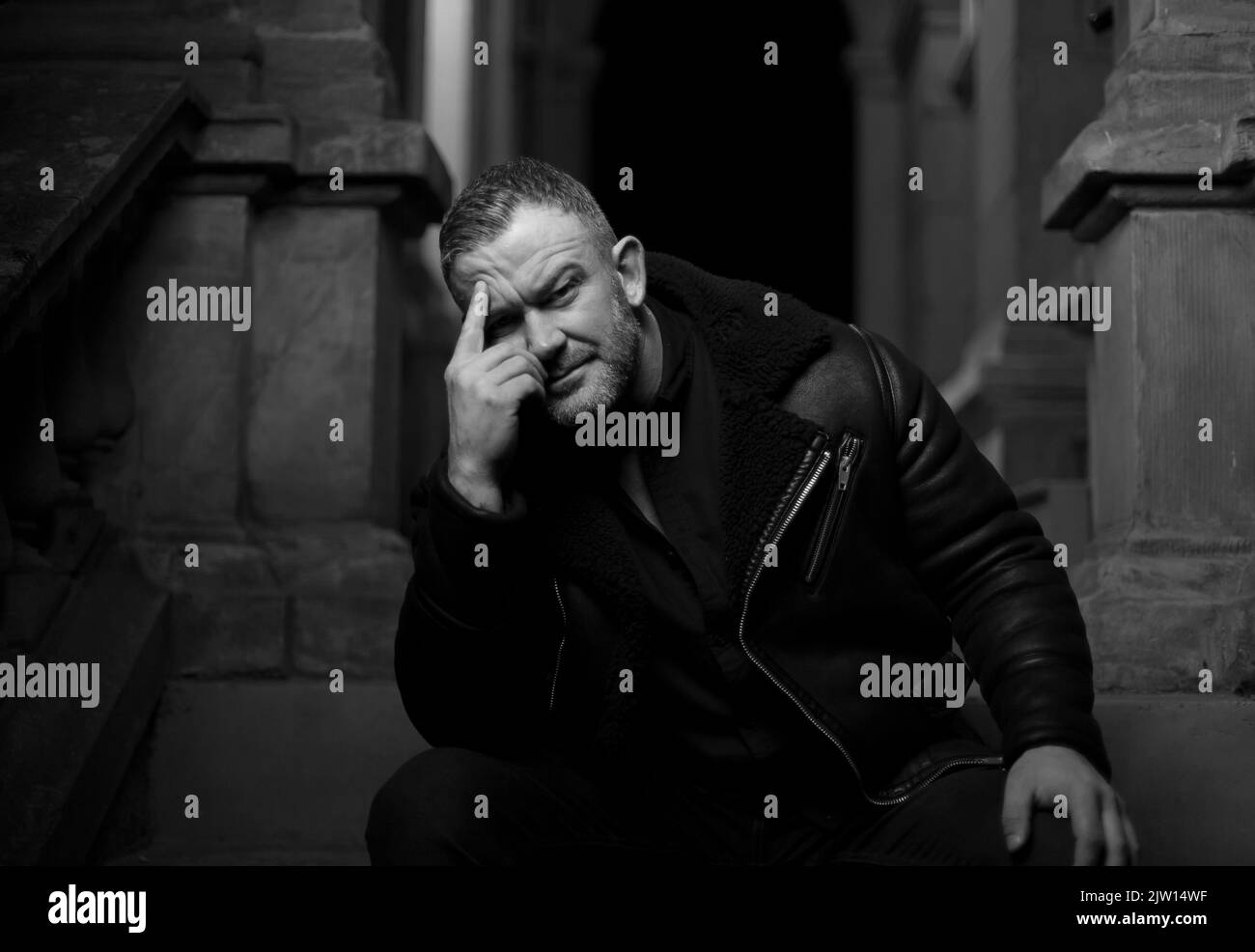 Caucasian mate sits on steps looking into camera with head resting on ...