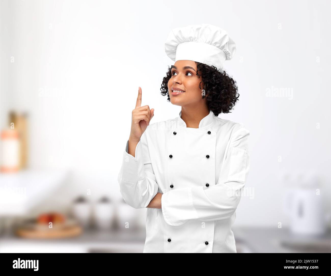 smiling female chef pointing finger up in kitchen Stock Photo - Alamy