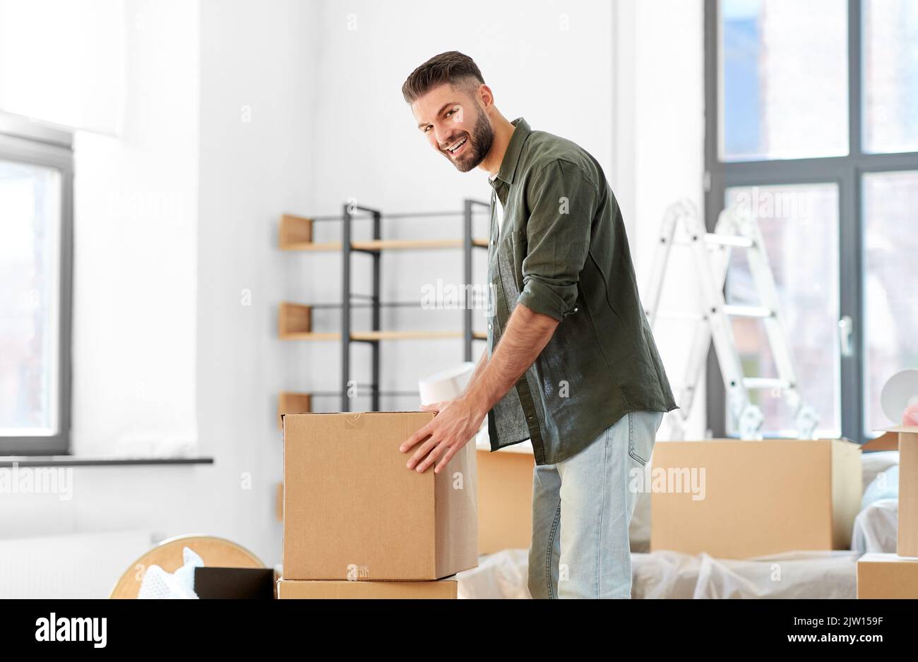 happy man with boxes moving to new home Stock Photo - Alamy