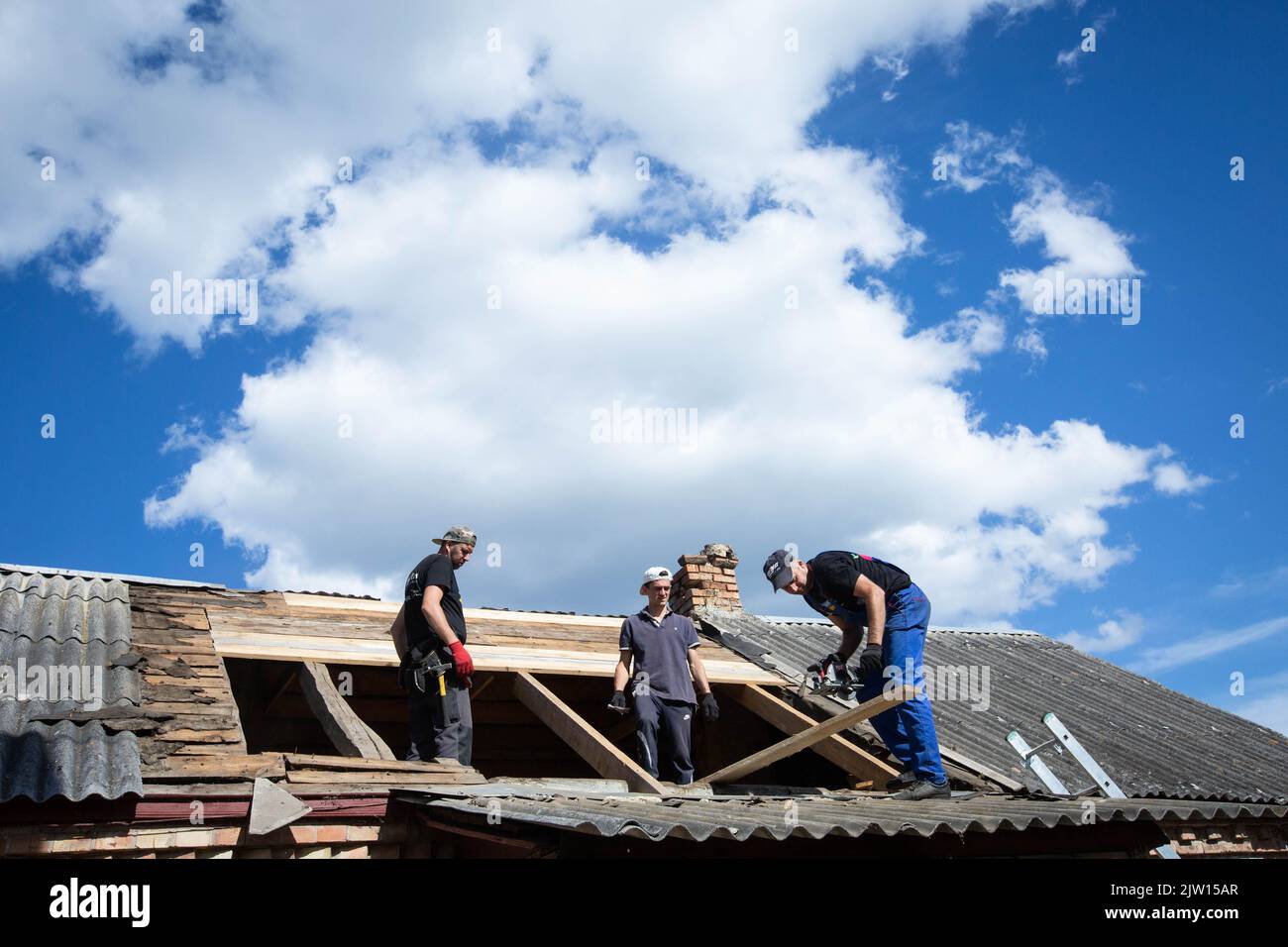 Volunteers repair the roof destroyed by Russian artillery shelling in ...