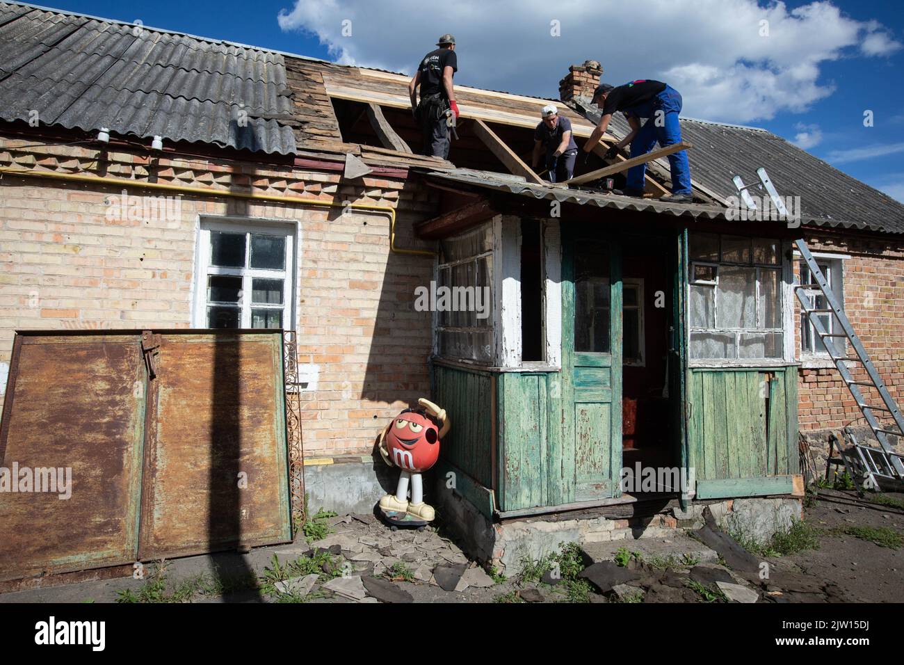 Volunteers repair the roof destroyed by Russian artillery shelling in ...