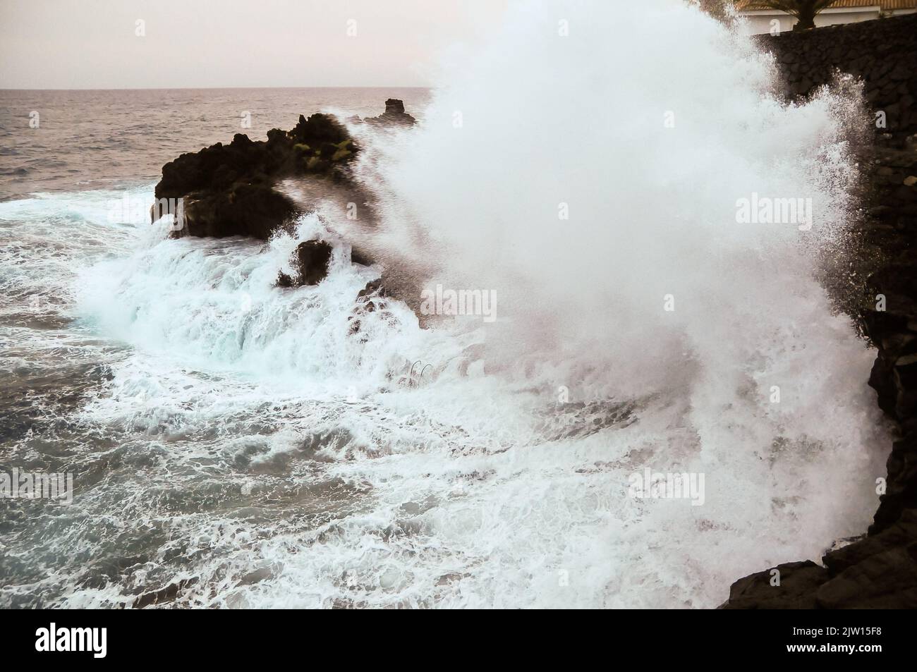 A shot of a strong wave hitting a cliff on the coast side Stock Photo ...