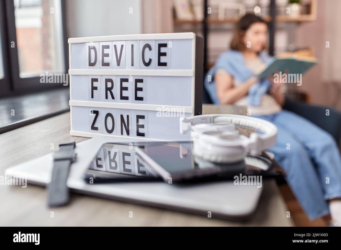 gadgets at device free zone and woman reading book Stock Photo - Alamy