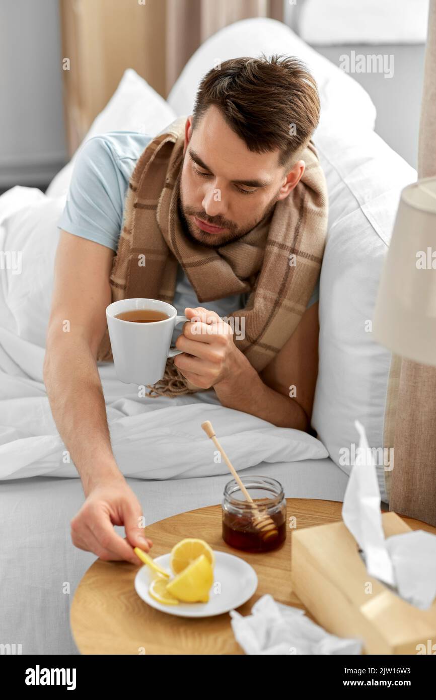 sick man drinking hot tea in bed at home Stock Photo - Alamy