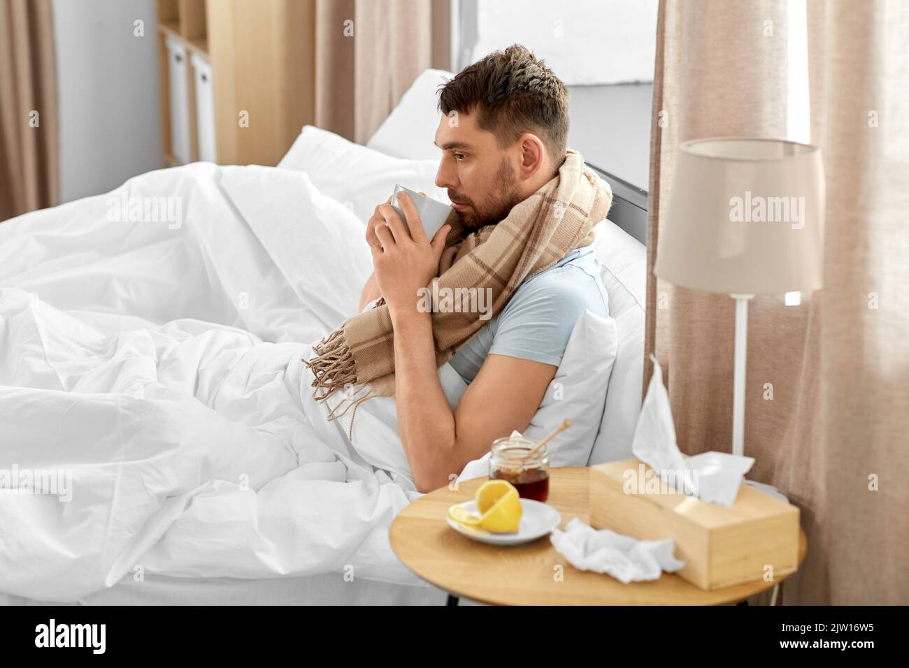 sick man drinking hot tea in bed at home Stock Photo - Alamy