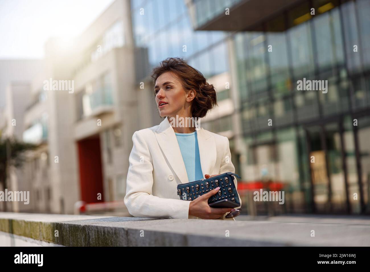 Focused woman in white suit standing near business centre. Blurred ...