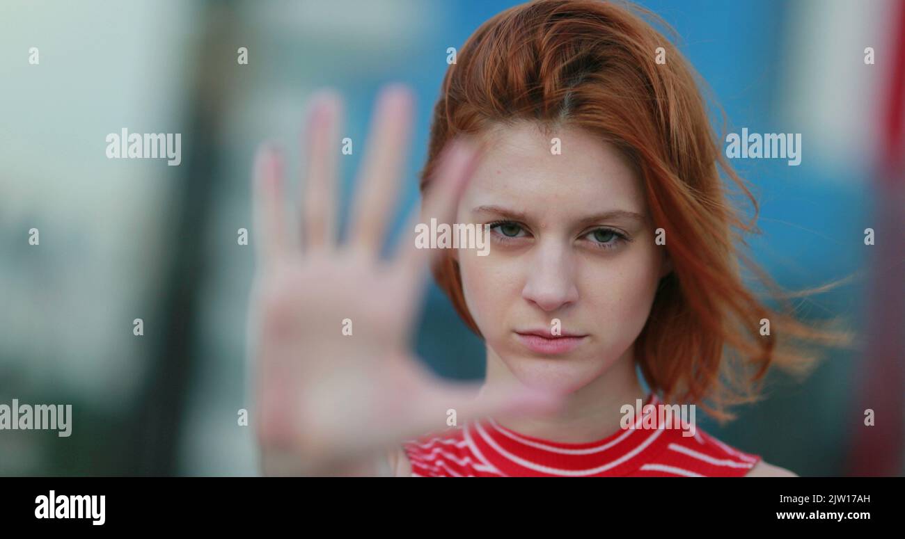 Assertive woman making stop gesture. Strong redhead lady showing hold ...