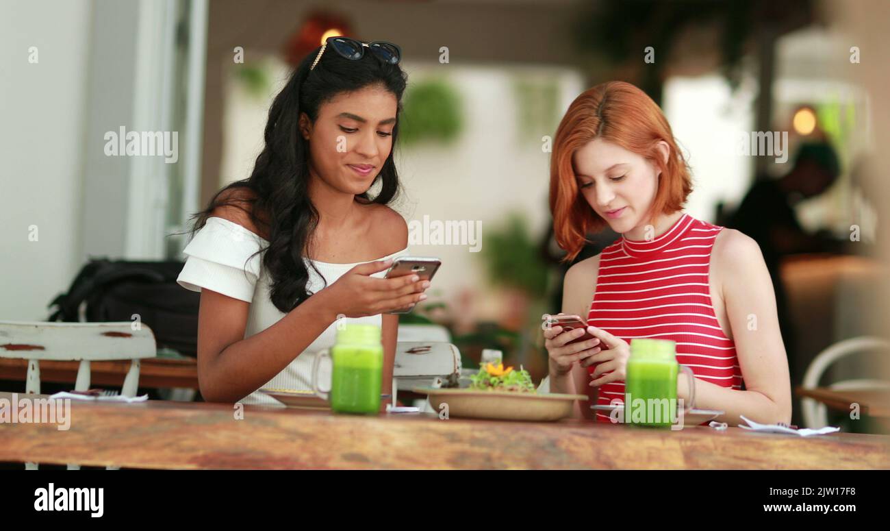 Attractive girls at restaurant, friend showing screen to female ...