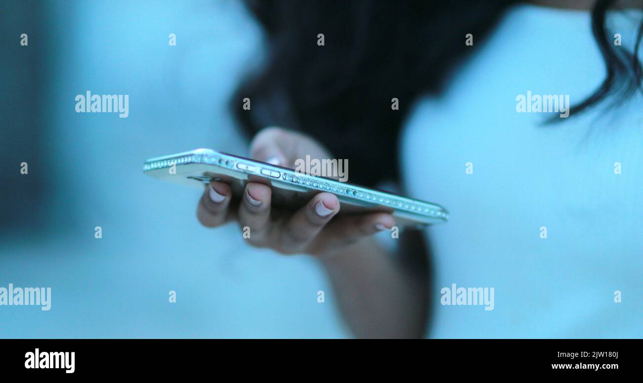 African multi-ethnic girl holding smartphone watching content standing ...