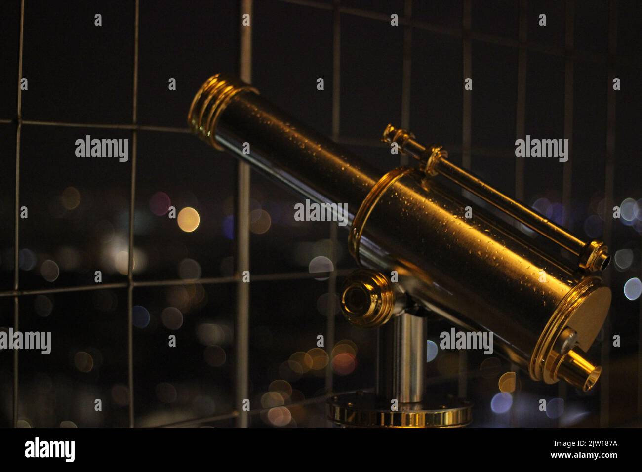 A vintage telescope in front of a window with a view of the starry sky ...
