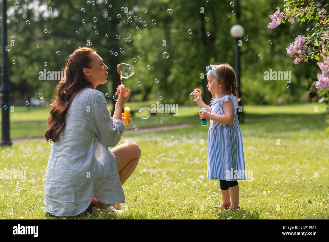 mother with daughter blowing soap bubbles at park Stock Photo - Alamy