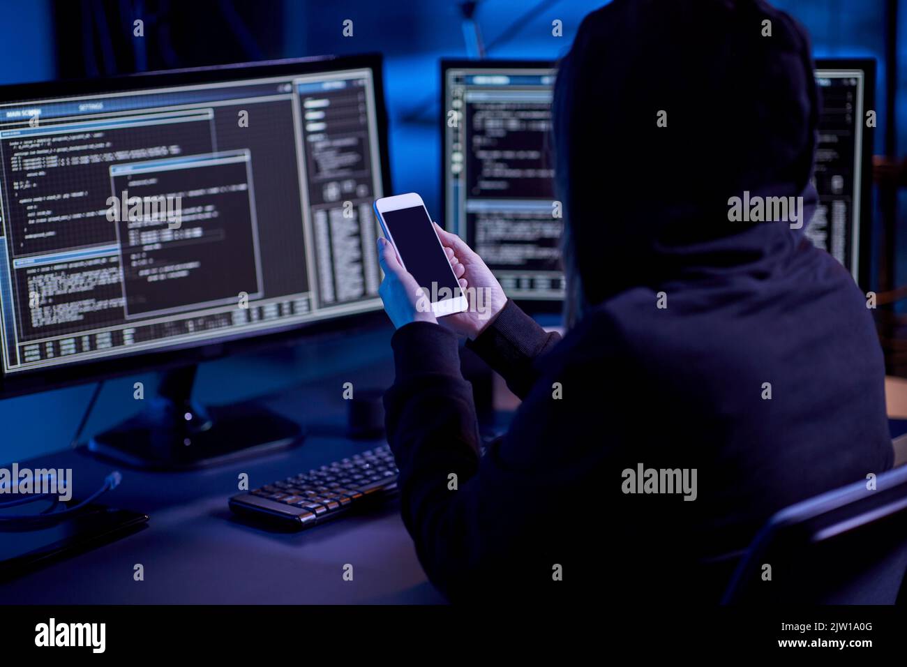 hacker with smartphone and computers in dark room Stock Photo - Alamy