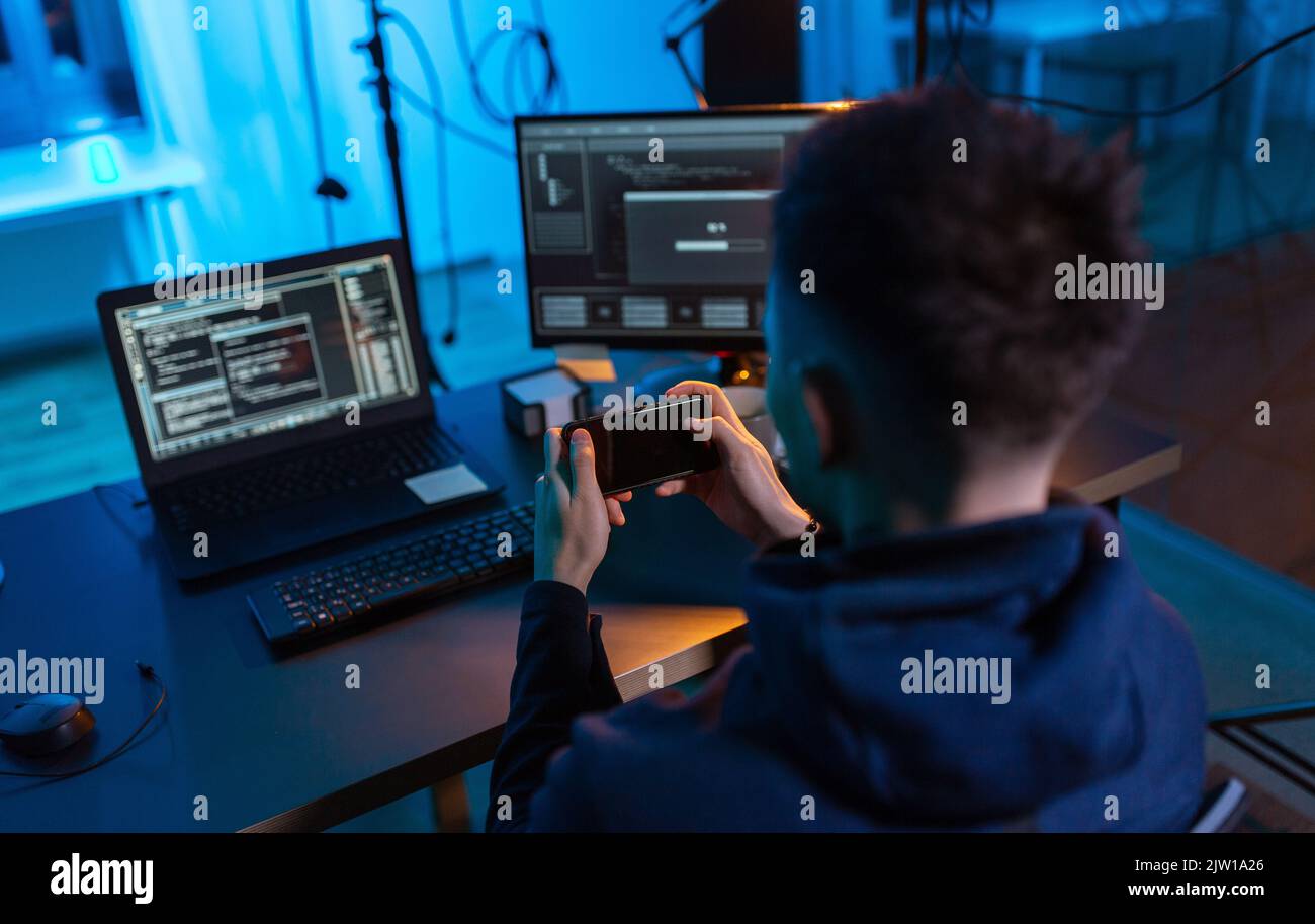hacker with smartphone and computers in dark room Stock Photo - Alamy