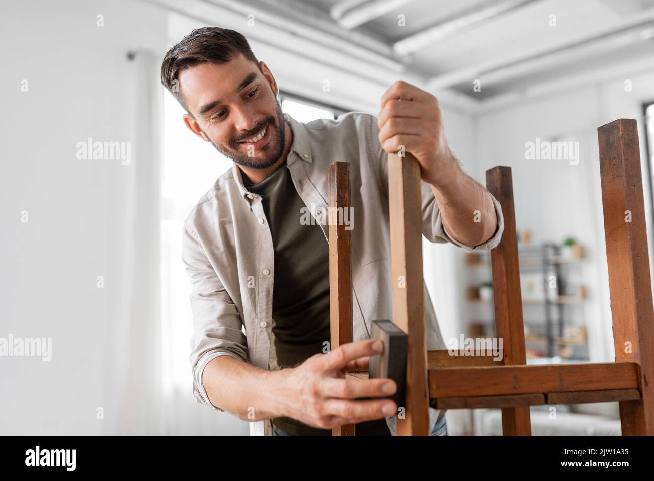man sanding old round wooden table with sponge Stock Photo - Alamy