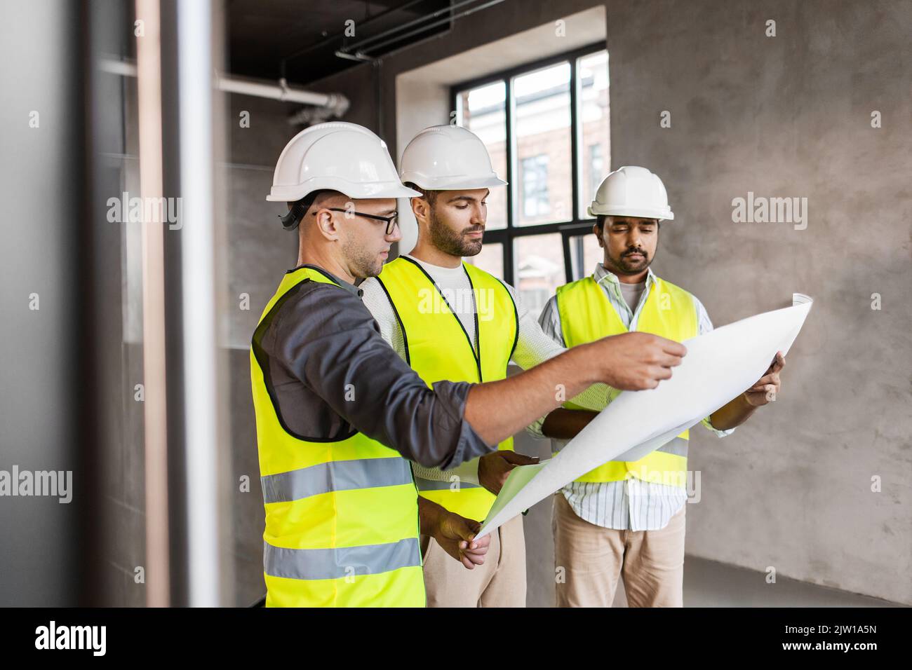 architects in helmets with blueprint at office Stock Photo - Alamy