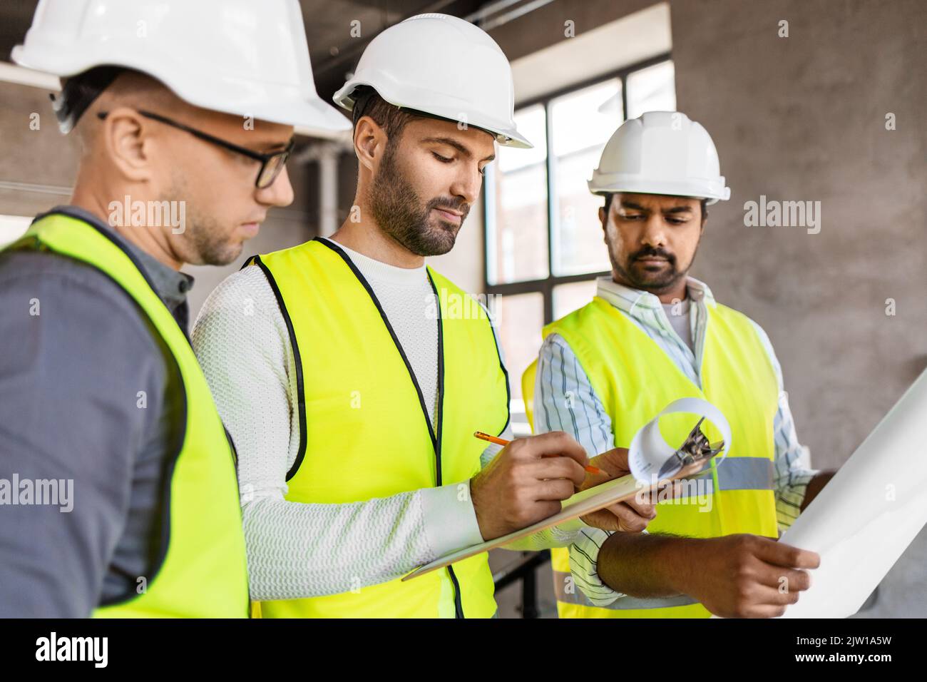 architects in helmets with blueprint at office Stock Photo - Alamy