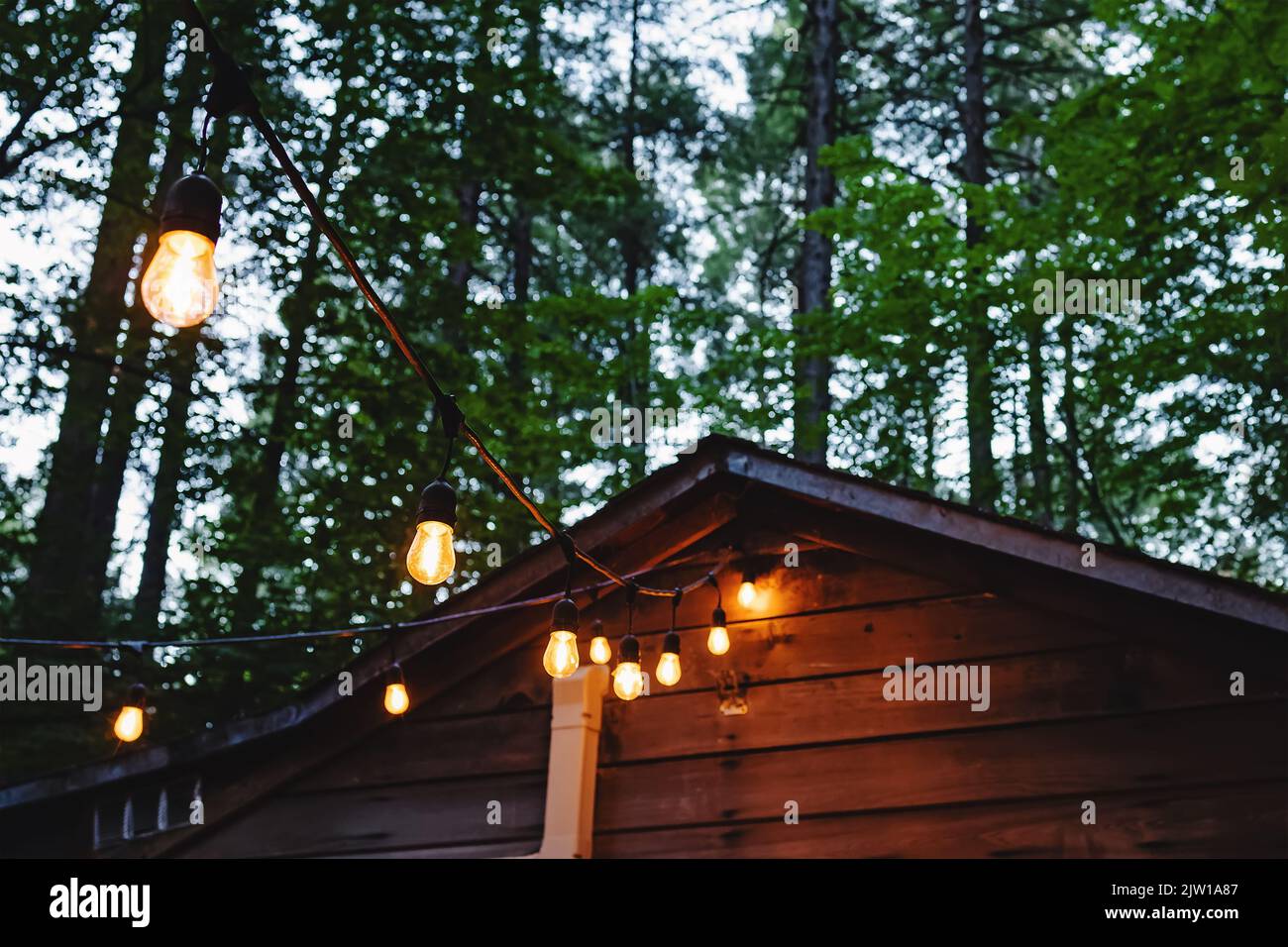Outdoor garland close-up. Warm lights on the patio of wooden cabin ...