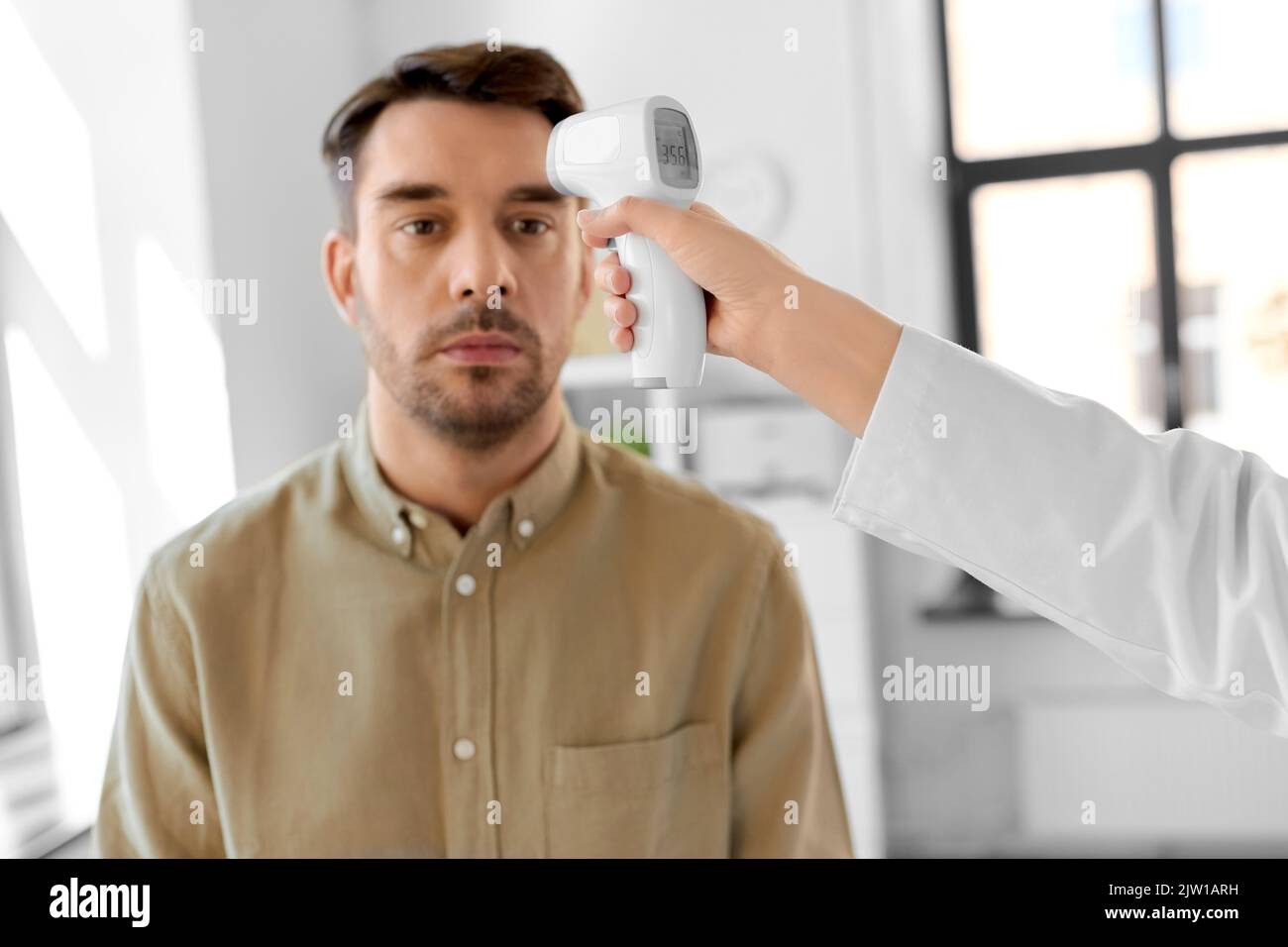 doctor with thermometer and man at hospital Stock Photo - Alamy