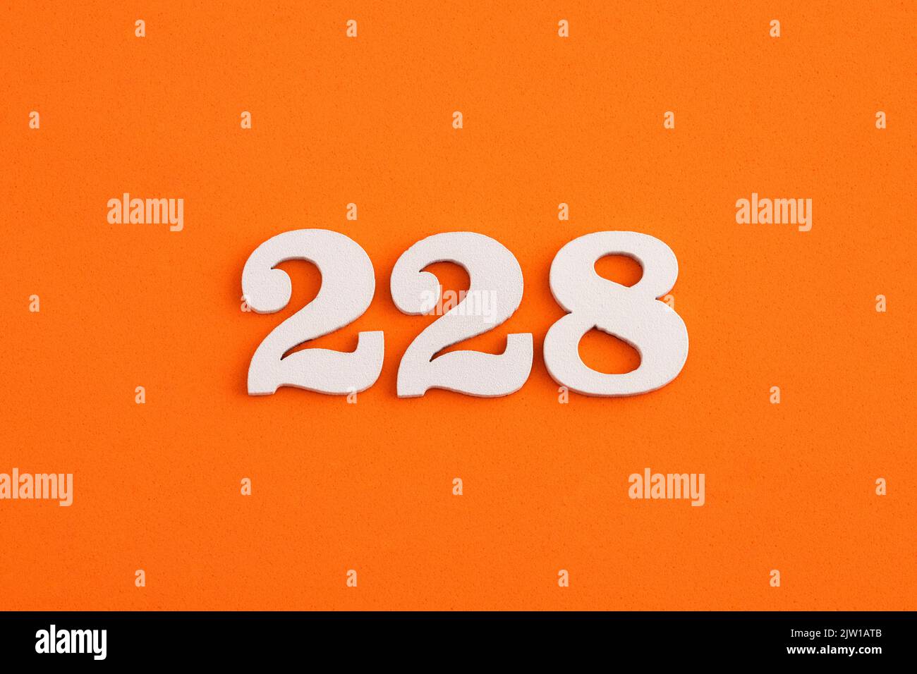 White wooden number 228 on eva rubber orange background Stock Photo - Alamy