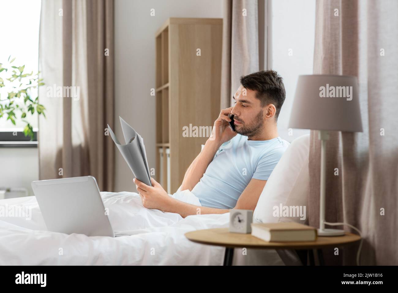 man with folder calling on phone in bed at home Stock Photo - Alamy