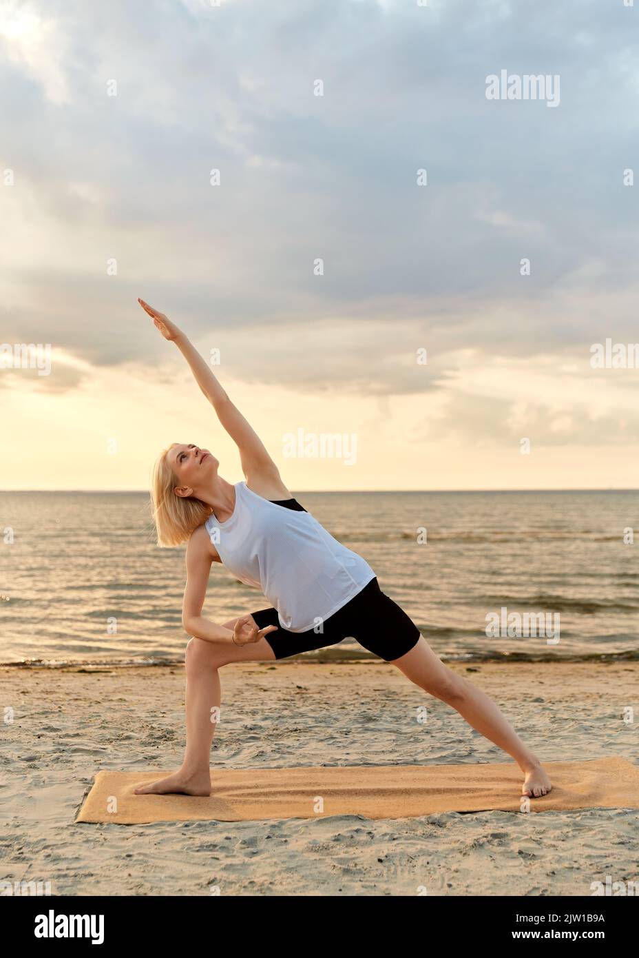 woman doing yoga triangle pose on beach Stock Photo - Alamy