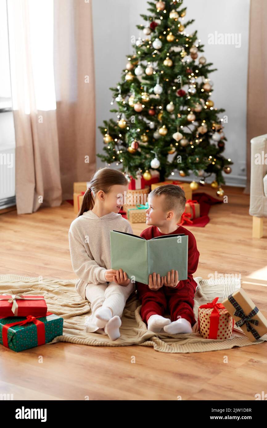 happy children reading book on christmas at home Stock Photo - Alamy