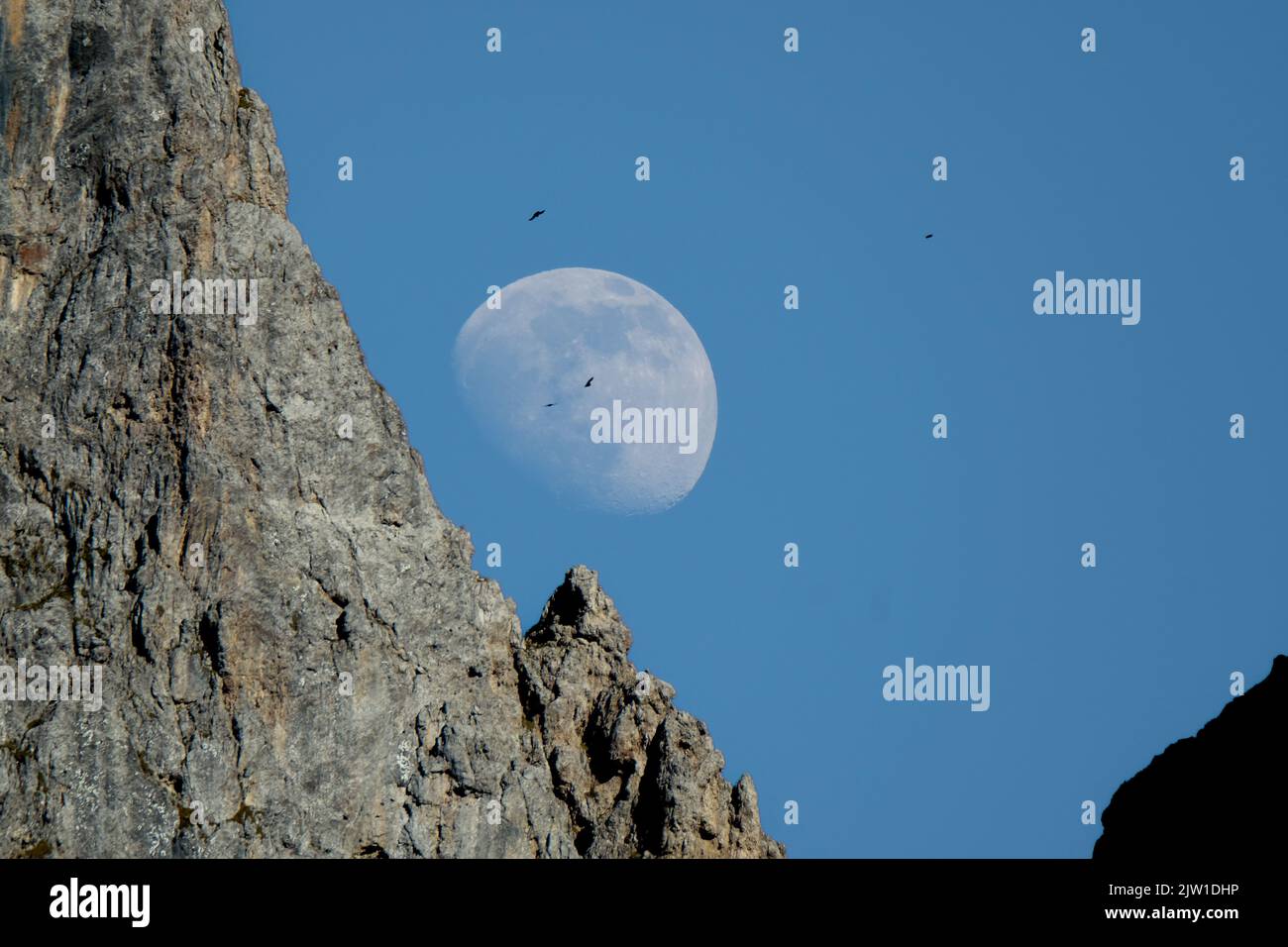 A rocky cliff with the fading moon in the background Stock Photo - Alamy