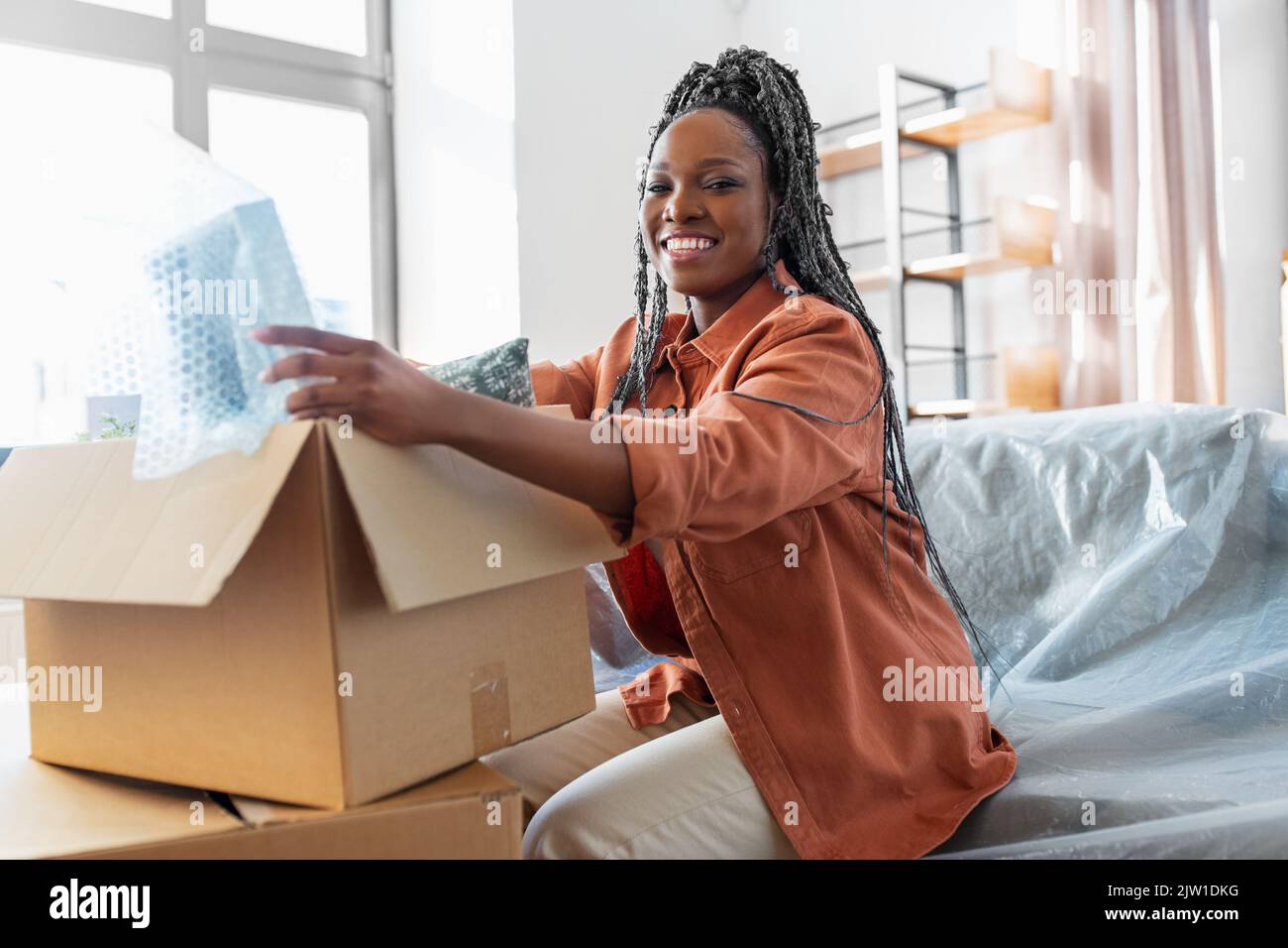 happy woman packing boxes and moving to new home Stock Photo - Alamy