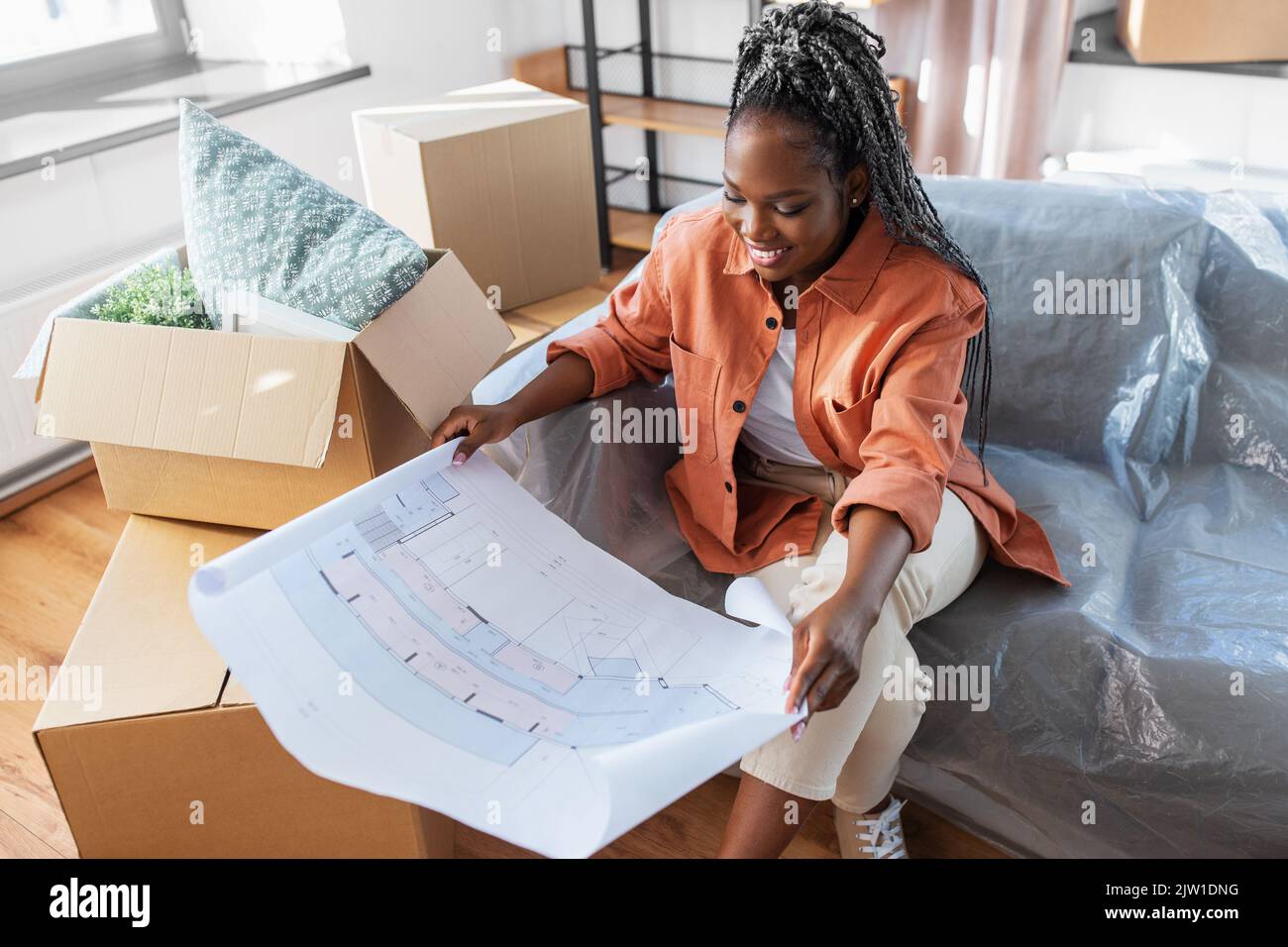 woman with blueprint and boxes moving to new home Stock Photo - Alamy