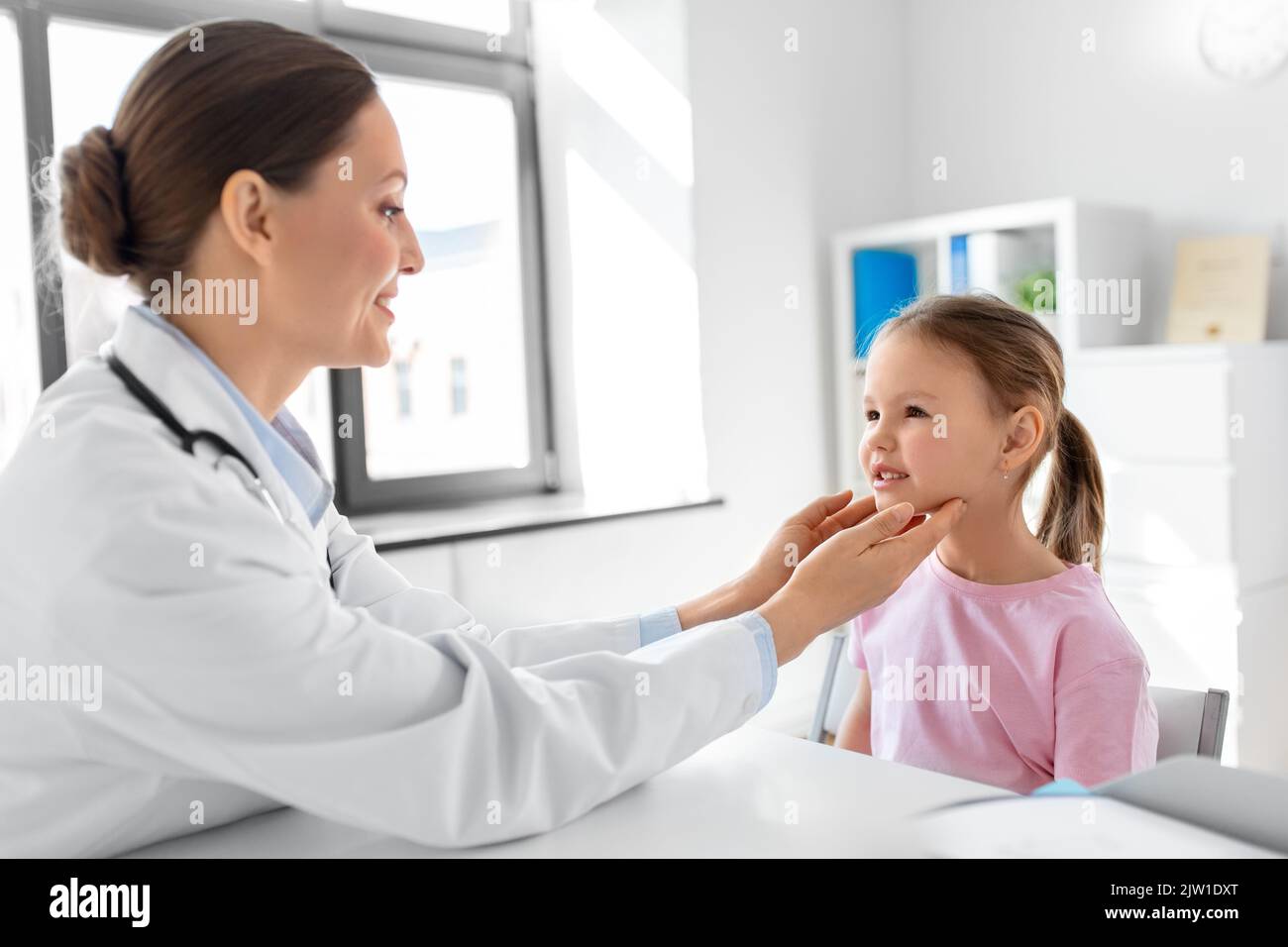 doctor checking girl patient's tonsils at clinic Stock Photo - Alamy