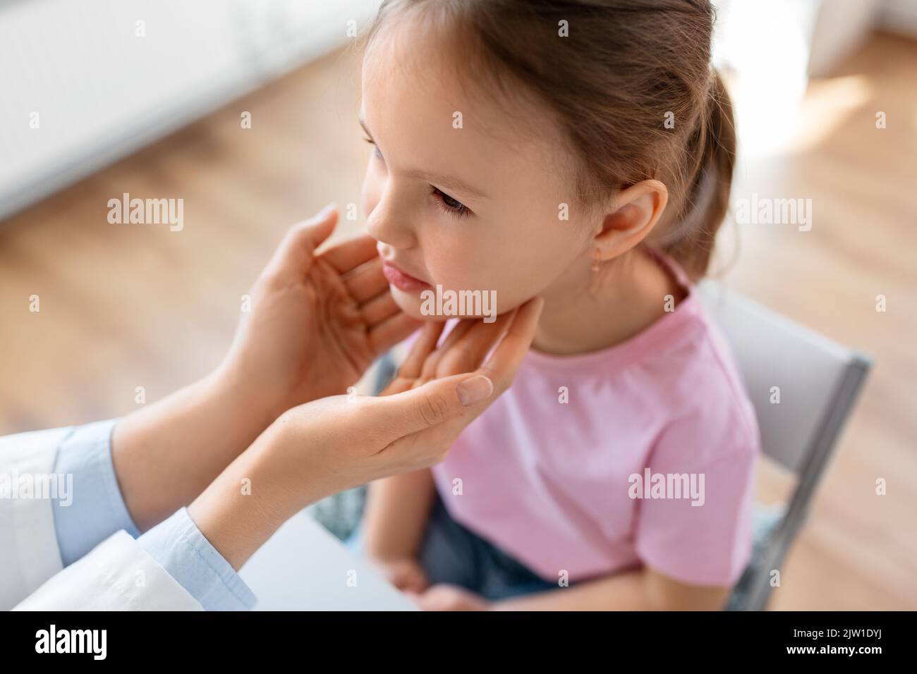 doctor checking girl patient's tonsils at clinic Stock Photo - Alamy