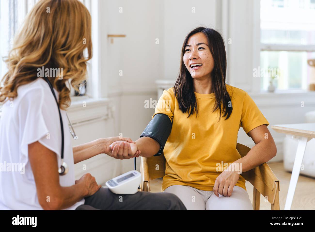 Happy female patient looking at doctor checking her pulse in hospital ...