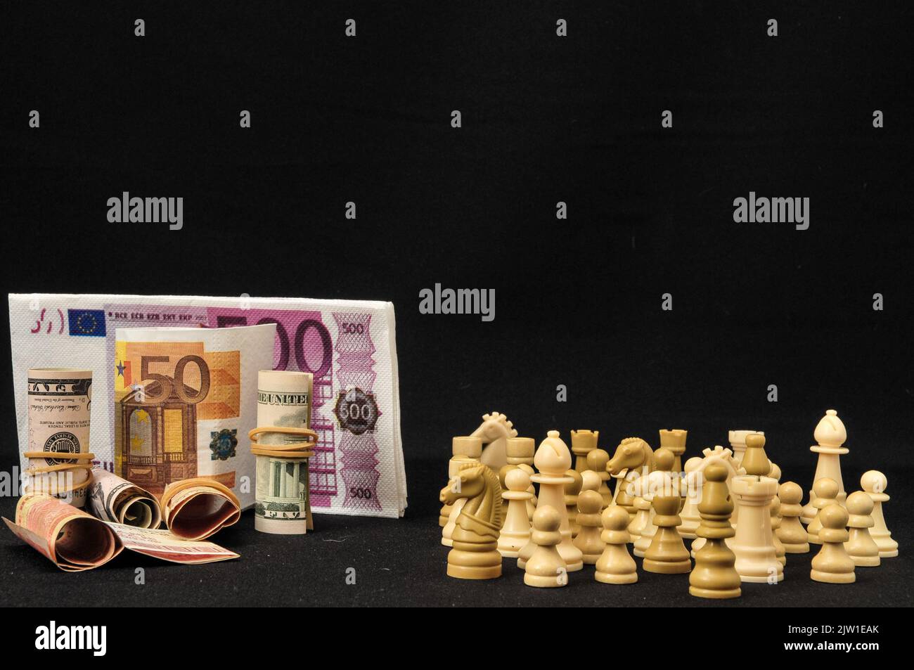 Banknotes and white chess pieces isolated on a black background ...