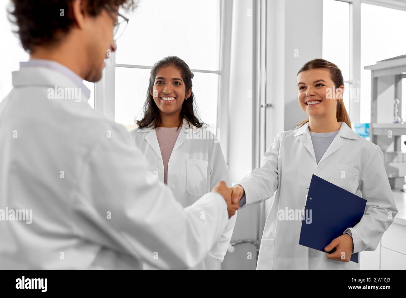 scientists shaking hands in laboratory Stock Photo - Alamy