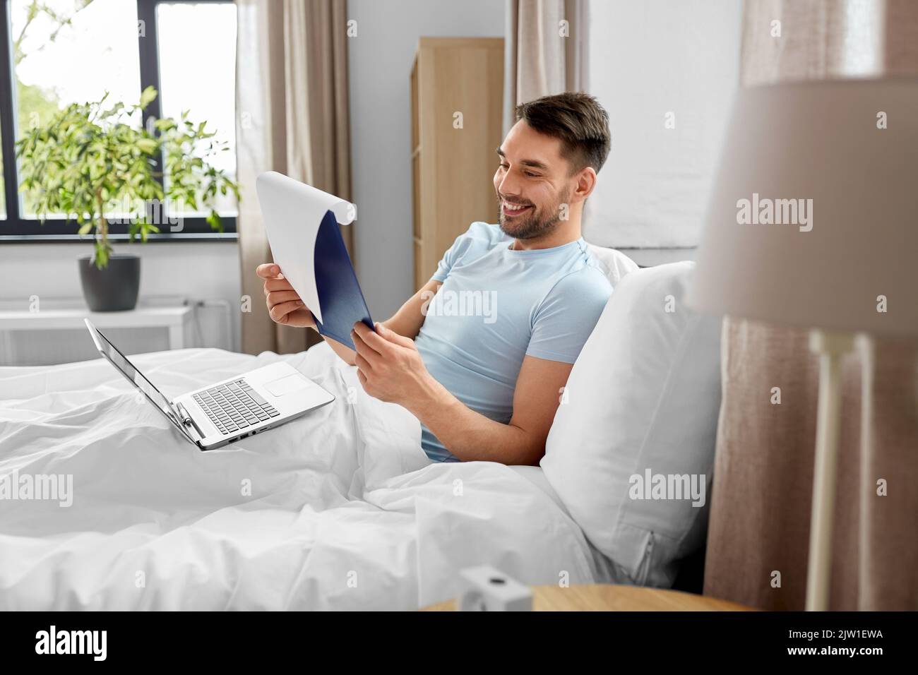 man with laptop working in bed at home bedroom Stock Photo - Alamy