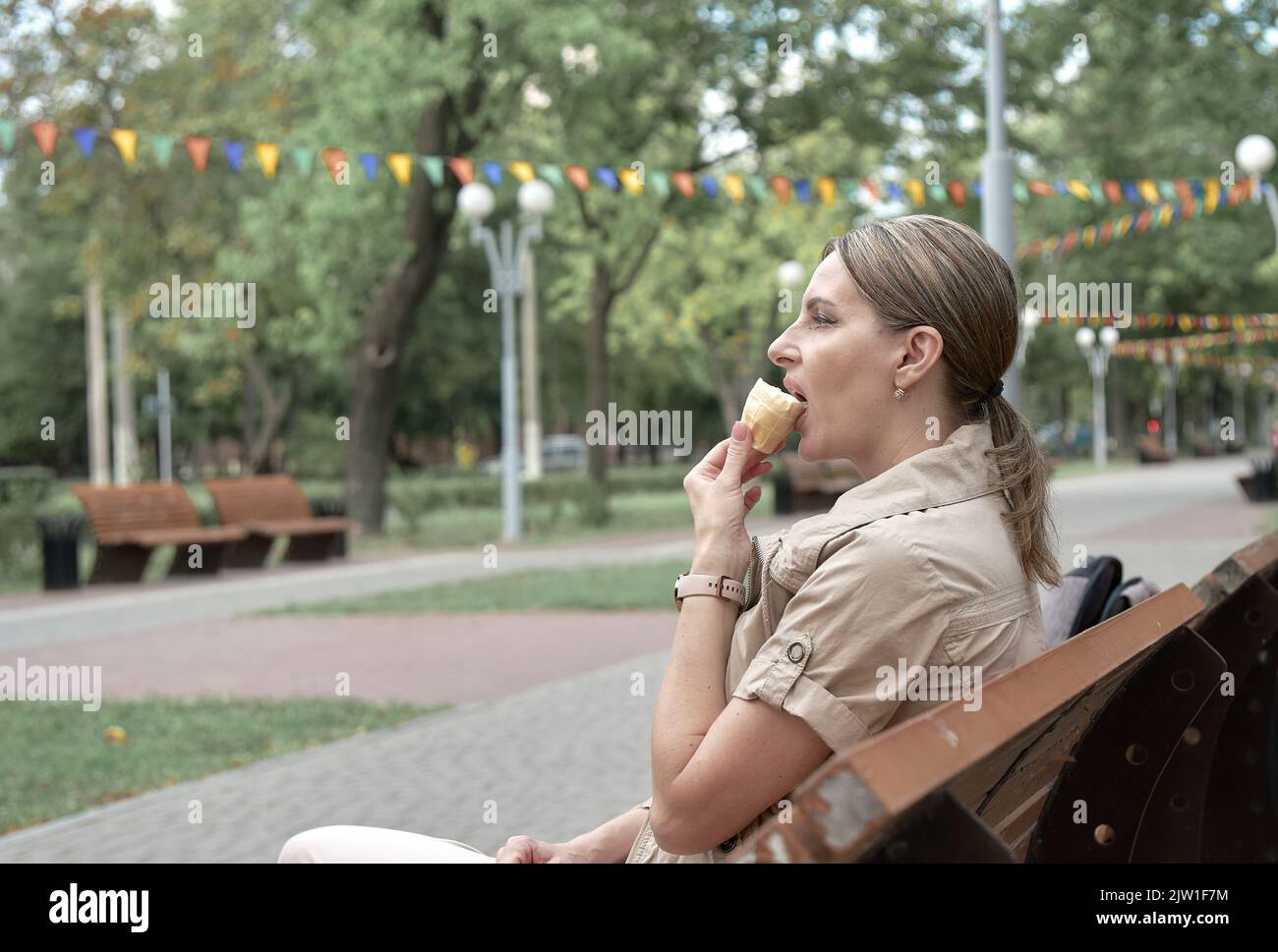 One woman sits alone on park bench eating ice cream Stock Photo - Alamy