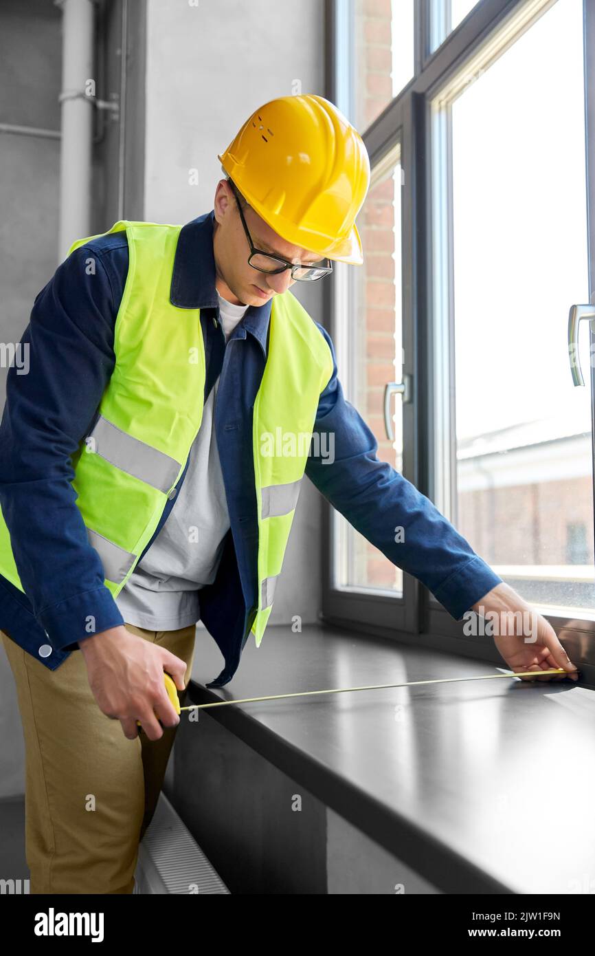 male builder with ruler measuring window sill Stock Photo - Alamy