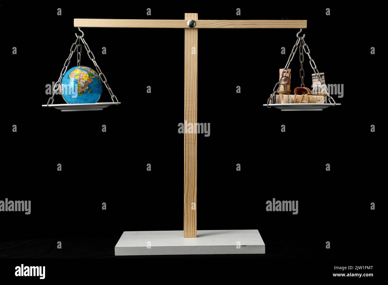 A scale weighing the of Globe Planet Earth and Money on a Two Pan ...