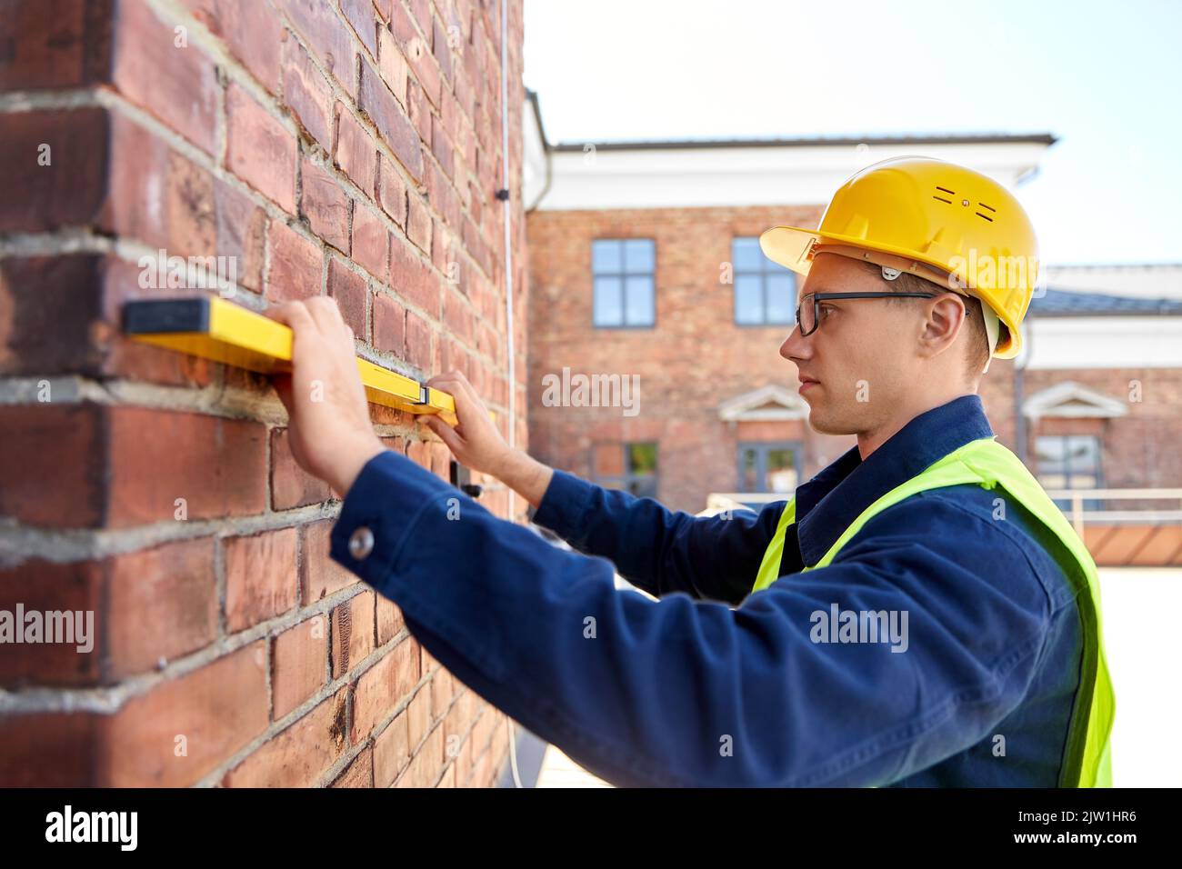 male builder with level measuring wall Stock Photo - Alamy