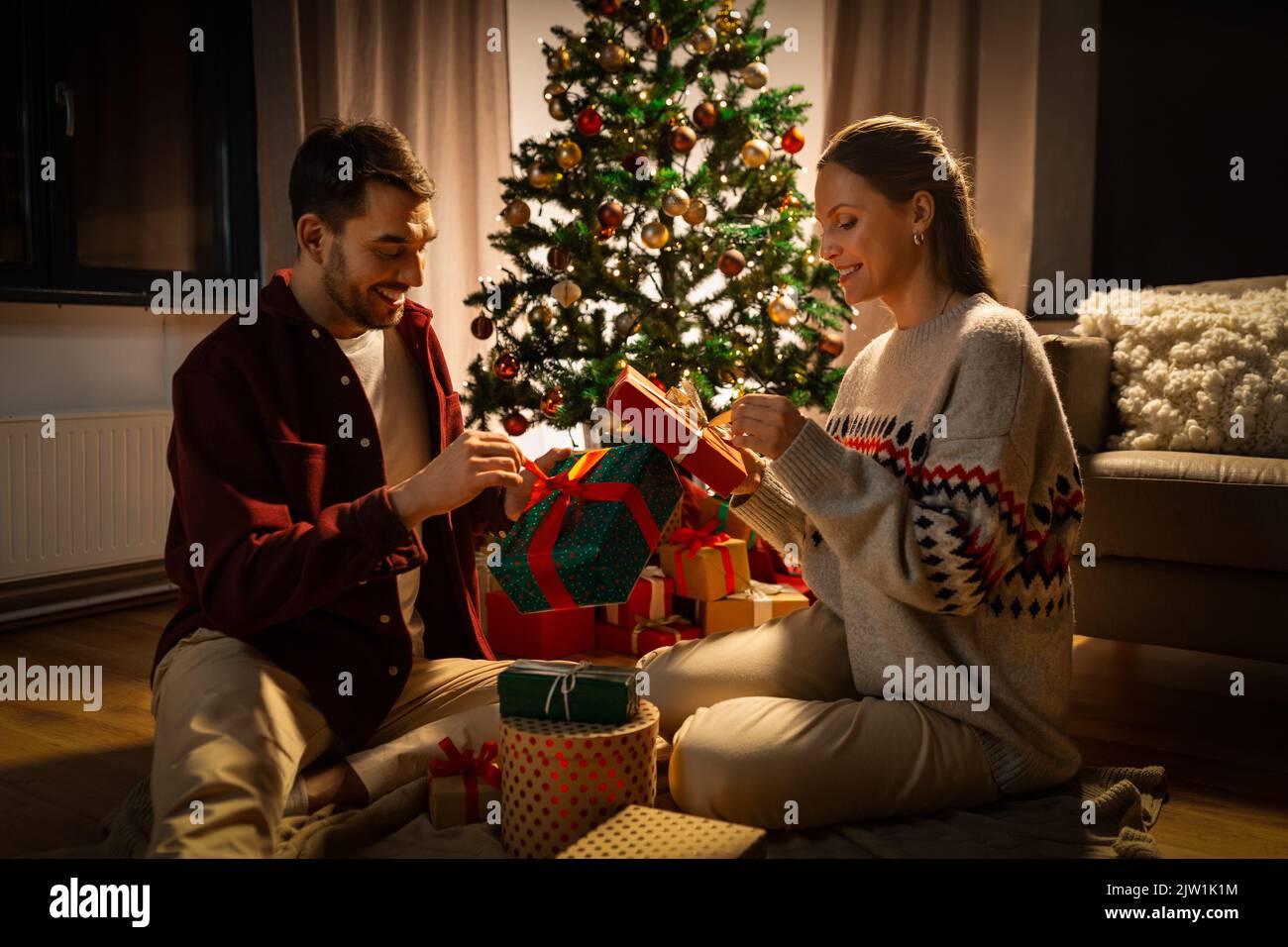 happy couple opening christmas gifts at home Stock Photo - Alamy