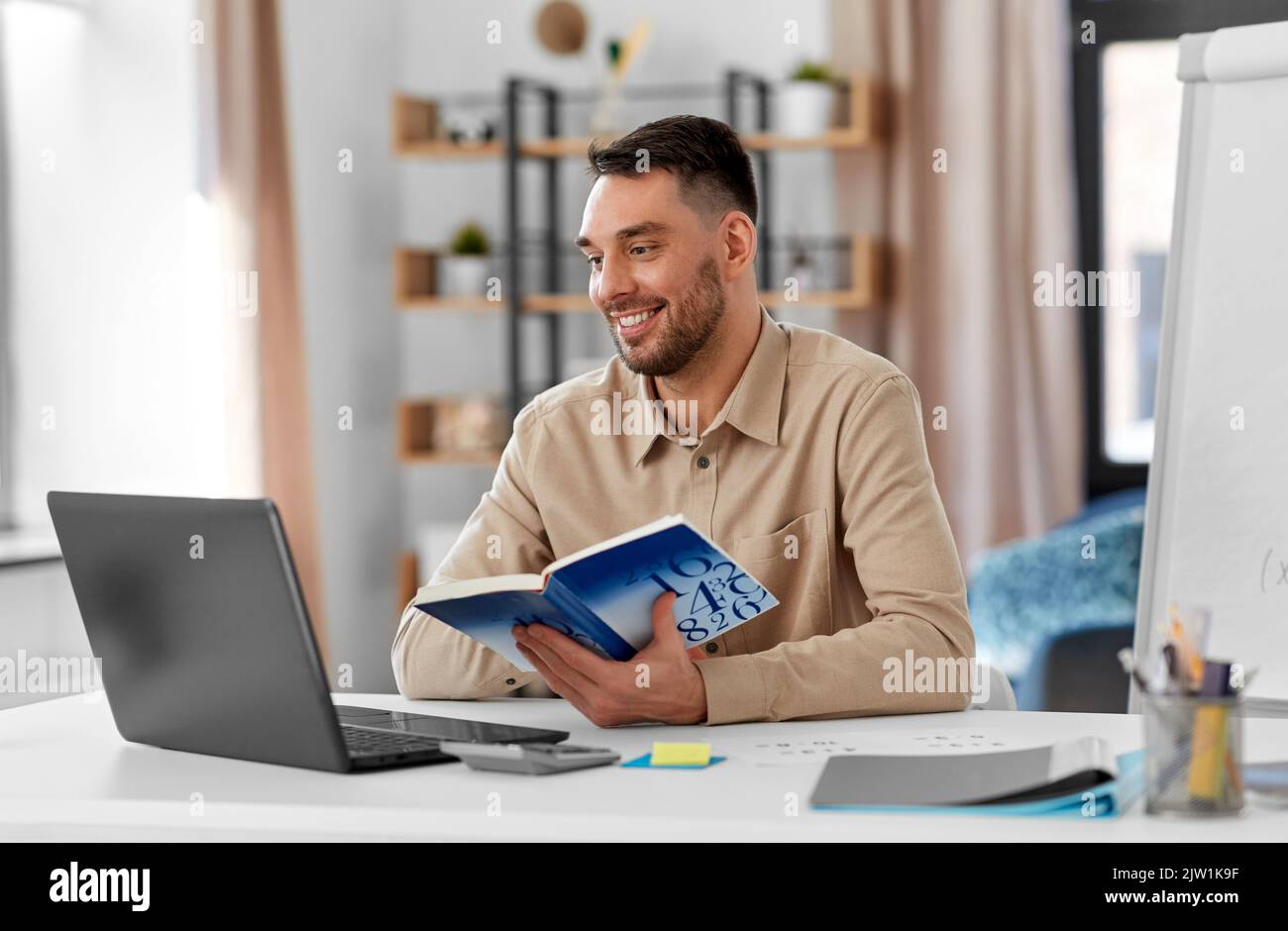 math teacher with laptop and book at home office Stock Photo - Alamy