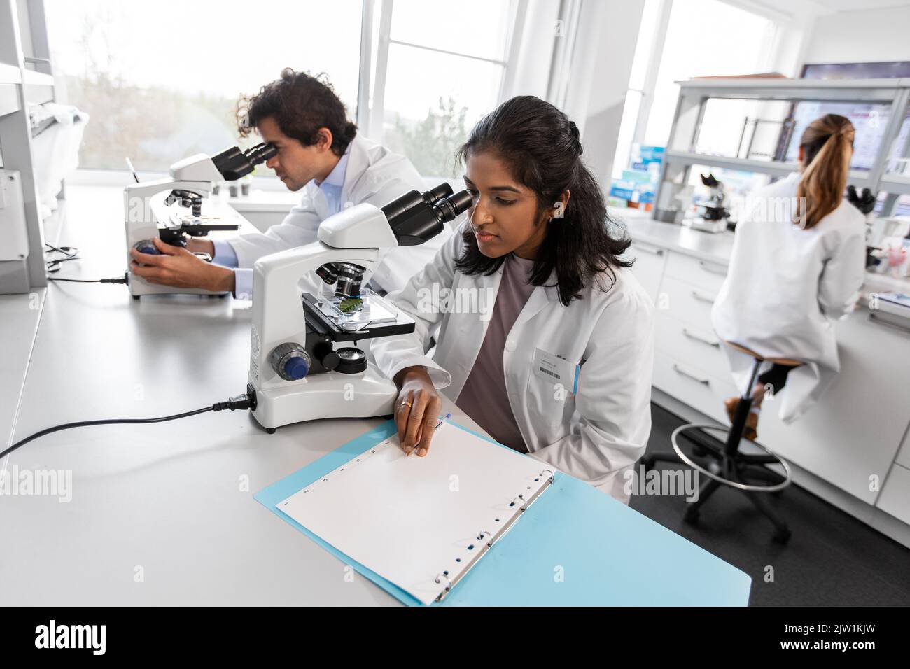 scientists with microscopes working in laboratory Stock Photo - Alamy