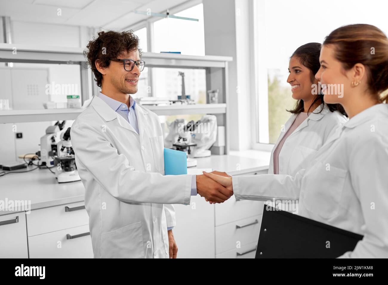 scientists shaking hands in laboratory Stock Photo - Alamy