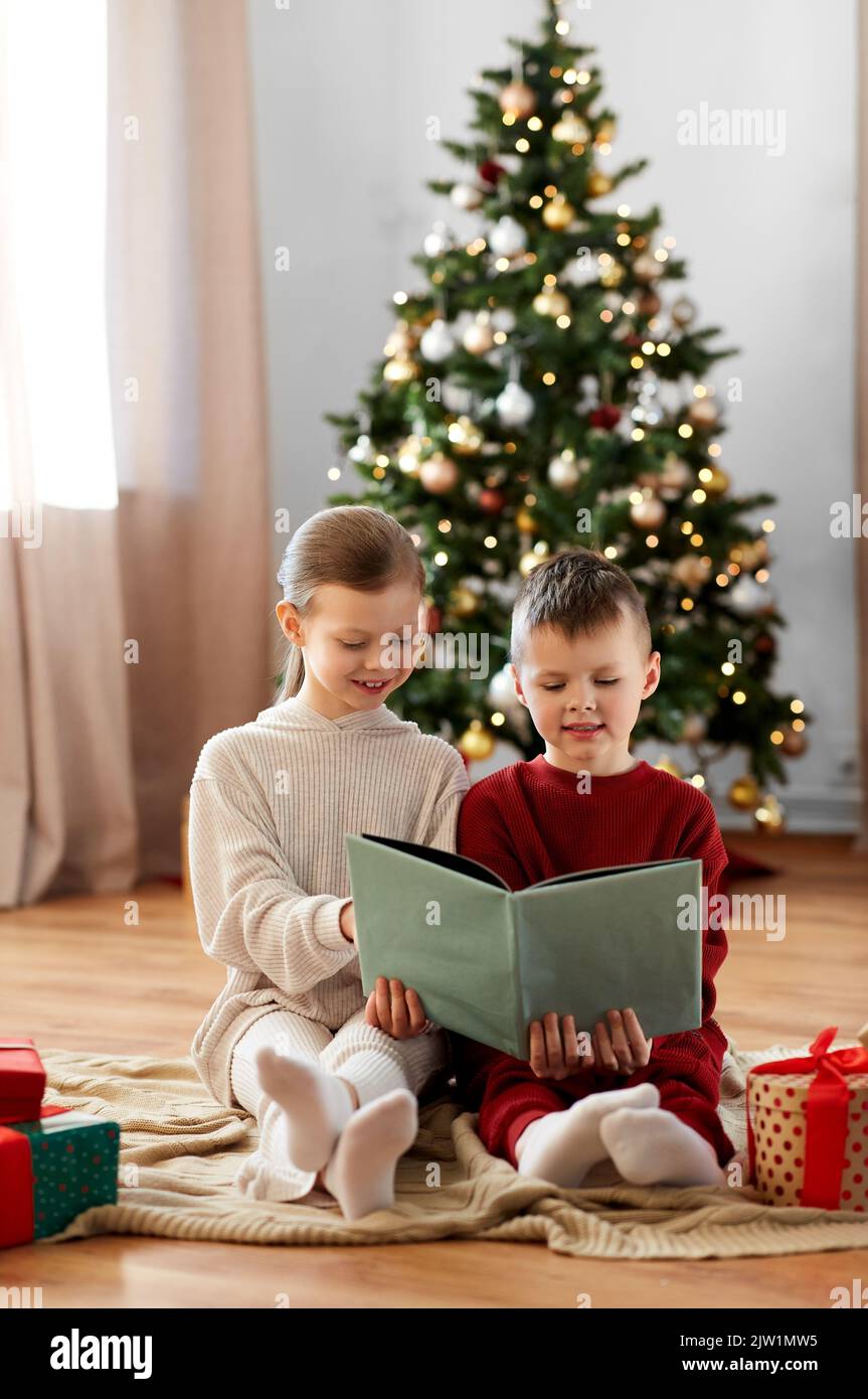 happy children reading book on christmas at home Stock Photo - Alamy