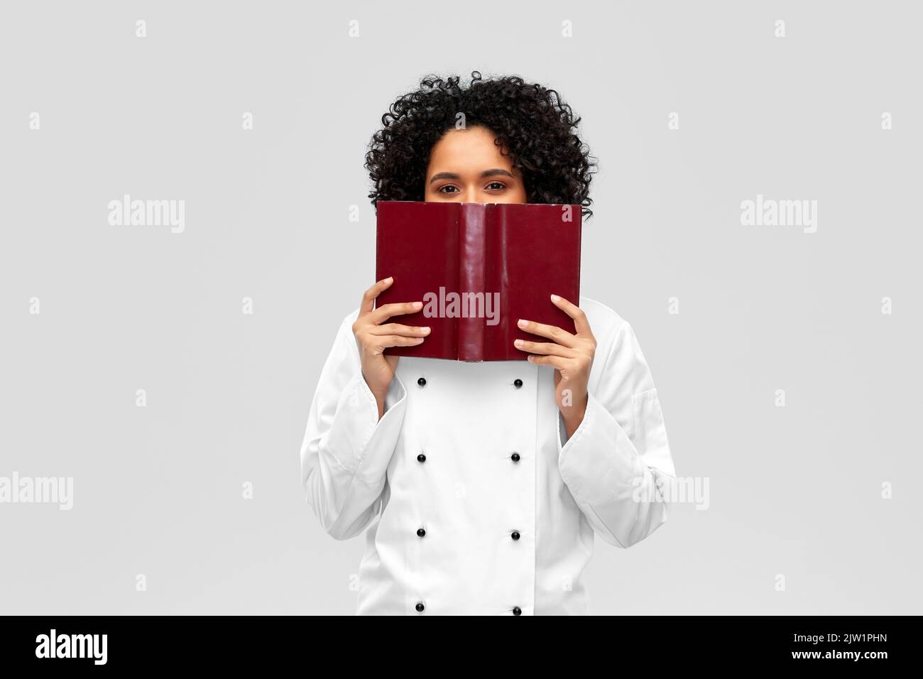female chef hiding behind cook book Stock Photo - Alamy